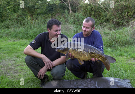 Men holding carp they've just caught on lake in Gloucestershire England ...