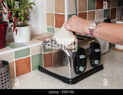 man places slice of bread in a toaster Stock Photo - Alamy