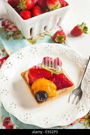 Delicious dessert. Tartlets with cream, berries and flowers on light ...