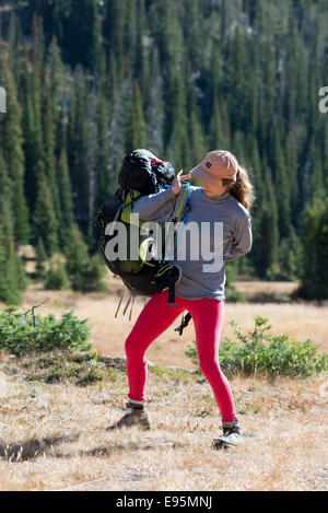 A woman putting on her backpack Stock Photo - Alamy
