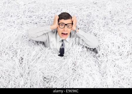 Shocked man looking at a pile of shredded paper isolated on white ...