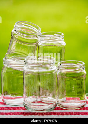 empty clear glass jam jars with a green background Stock Photo - Alamy