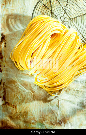 Dried Italian linguine or tagliatelli pasta in coils lying on a rustic ...