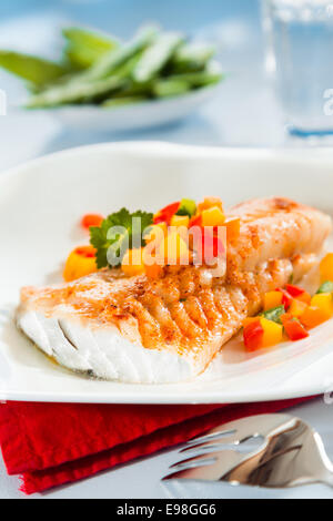 Grilled fish fillet served with colorful mixed vegetables on black ...