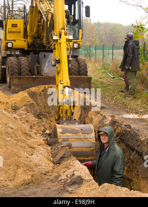 Workers are digging a deep hole with digger Stock Photo - Alamy