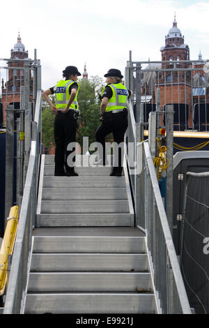 BACK VIEW OF TWO POLICE OFFICERS, MALE AND FEMALE, WALKING DOWN THE ...