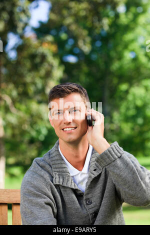 Young man phoning on the bench Stock Photo - Alamy