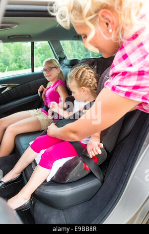 Mother buckling up on child in car safety seat Stock Photo - Alamy