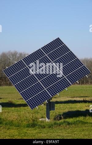 Rotating solar panel in a field set against a wooded area Stock Photo ...