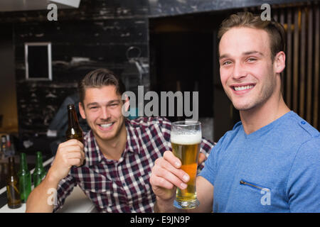 Handsome young man drinking a pint of beer screaming proud, celebrating ...