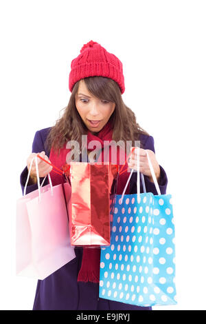 Shocked brunette opening gift bag against white background with ...