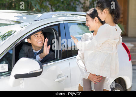Mother and daughter waving goodbye to father Stock Photo - Alamy
