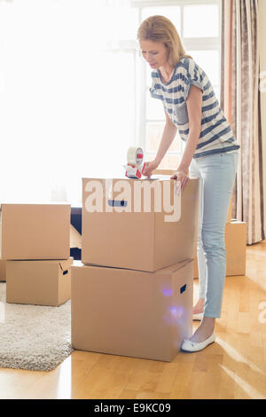 woman with adhesive tape packing box at new home Stock Photo - Alamy