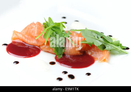 Smoked salmon gravlax served as a starter on a white plate with chilli ...