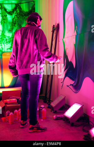 Graffiti artist, wearing a breathing mask, using a spray can on ...