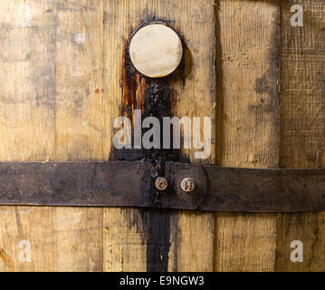 A wooden whiskey barrel leaking bourbon through the slats as it sits on ...