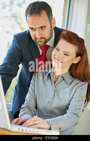 Two young beautiful businesswoman discussing in a meeting looking at ...