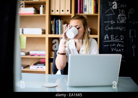 Female graphic designer using laptop at desk Stock Photo - Alamy