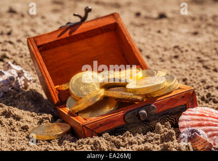 Open treasure chest filled with gold colored coins and compass over ...