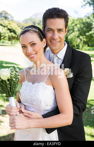 Handsome groom hugging sensual bride from behind on background of an ...