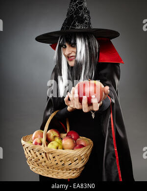 Tricky witch offering a poisoned apple, Halloween theme Stock Photo - Alamy