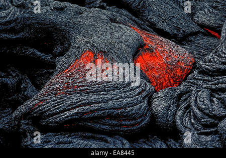 Molten lava rock that glows from its extreme heat flows from an ...
