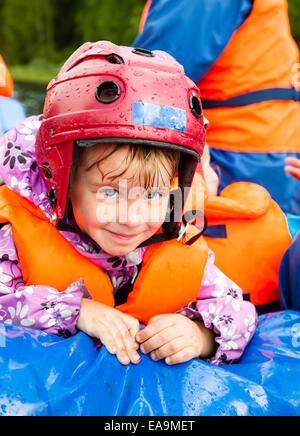 Little girl sitting in a raft on a river with lush greenery Stock Photo ...