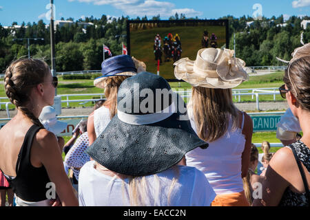 Female horse racing fans wearing hats watching the start of a turf ...