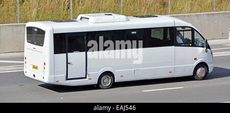 A small white tour coach, bus or mini-van used to transport passengers ...