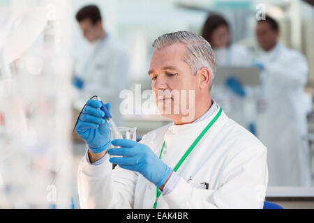 Middle age man scientist looking test tube holding clipboard at ...