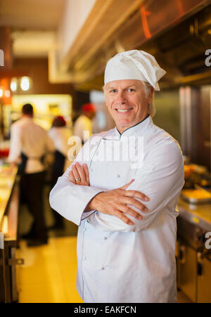 Smiling Male Chef in uniforms preparing sushi in a kitchen of asian ...
