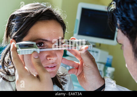 a young ophthalmologist using an exophthalmometer, an instrument used ...
