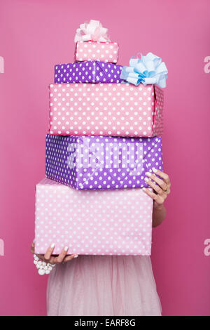 Christmas pink background with a gift, a woman's hand unpacks the gift ...