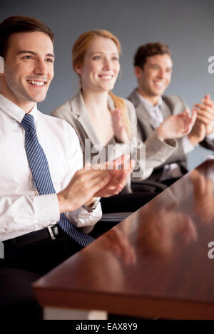 Smiling male and female professionals clapping during meeting in office ...