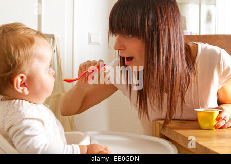 Mother feeding baby food to baby. Funny child face. Carefree childhood ...