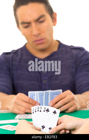 Young hispanic man playing poker holding dollars banknotes and chips ...