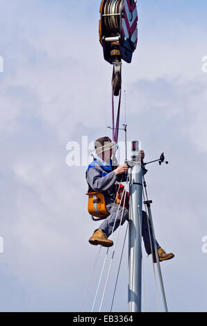 Workman seated in Bosun's Chair suspended from a crane working at the ...