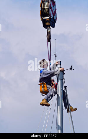 Workman seated in Bosun's Chair suspended from a crane working at the ...