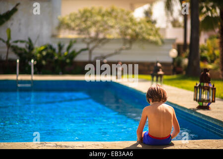 Boy sitting on the edge of the pool Stock Photo - Alamy