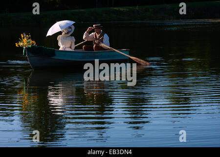 Victorian Couple in a rowboat at sunset toasting with wine glasses ...