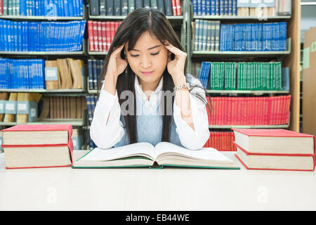 Young Asian student under mental pressure while reading book preparing ...