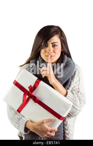 Festive brunette keeping secret and holding gift Stock Photo - Alamy