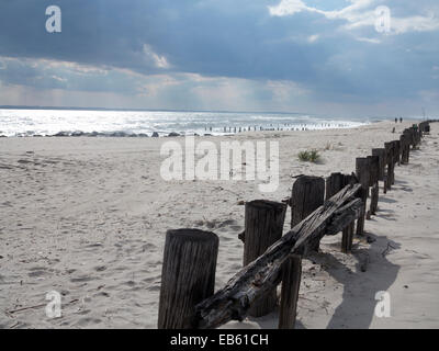 Wooden docks in the ocean with the reflection of light of the sunset in ...