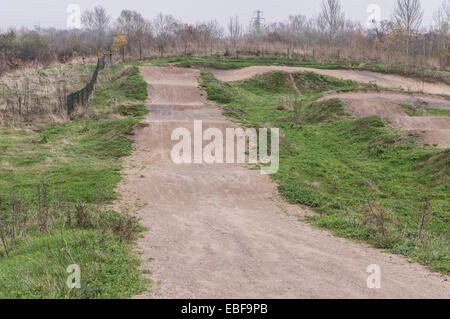 An empty, bumpy, dirt brown local BMX track verged with grass and ...