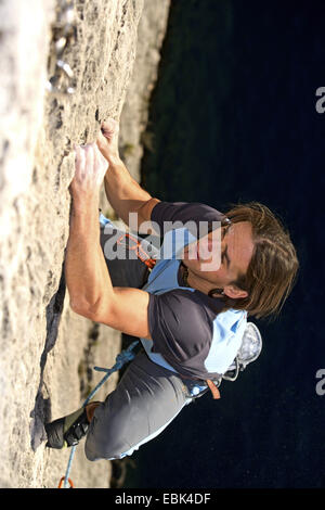 Man climbing up steep rocks with the chains. Omanawanui track in the ...