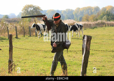hunter climbing over the barbed wire fence at a pasture, Germany Stock ...