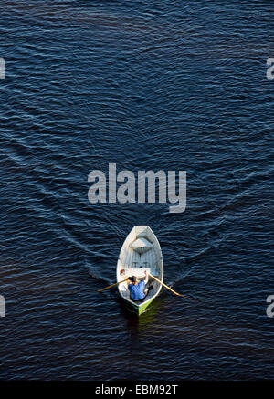 Aerial view of a man rowing a small fiberglass rowboat / skiff / dinghy ...