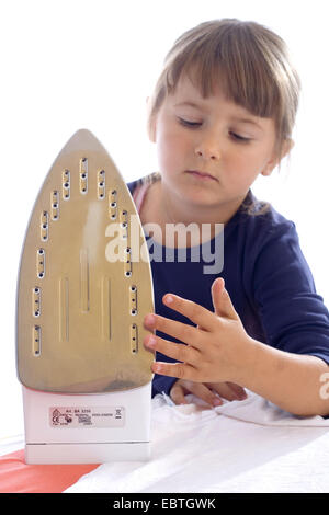 little girl touching carelessness a flat iron Stock Photo - Alamy