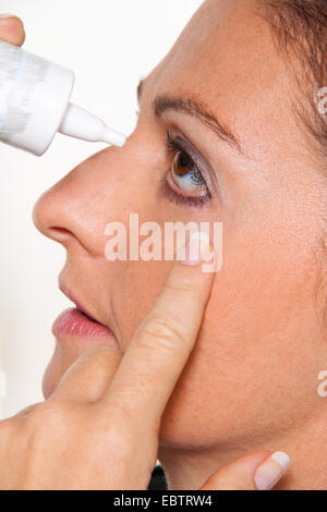 Allergic young woman with eye drops in park on spring day, closeup ...