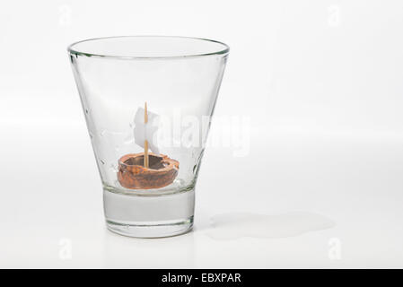 Macro of a walnut shell boat with a sail, floating in a transparent ...